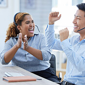 Two happy young call centre telemarketing agents clapping and cheering ...