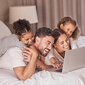 Happy family streaming movies on laptop in bedroom for online ...