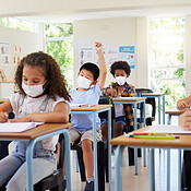 Young kids learning in classroom after covid pandemic, wearing ...