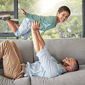 Children, family and love with a man and boy playing together on a sofa ...