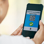 Hand phone, vaccine qr code and covid app on screen with registration ...