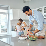 Mom, dad and child cooking in kitchen together to prepare food for ...