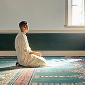 Mosque, worship and muslim man in prayer on his knees for gratitude ...