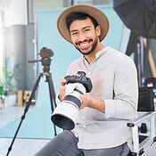 Portrait, photographer and man with camera in studio, happy and smile ...