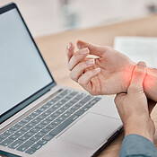 Laptop, office and business woman with wrist pain, injury or accident ...