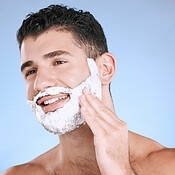 Shaving, foam on beard and man with smile and hand on face, product ...