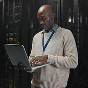 Server room, laptop and black man technician with data center ...
