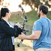 Target, training and archey woman with an instructor on field for hobby ...