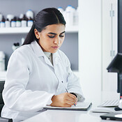 Young scientist using a computer and microscope in a lab. Female ...