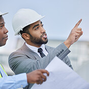 Engineering, teamwork and leader with blueprint at construction site ...