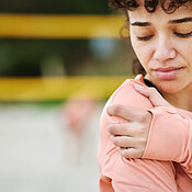 Shoulder pain, fitness and woman with injury at beach after volleyball ...
