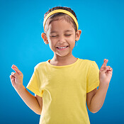 Child, hand and fingers crossed in studio for hope, wish or good luck ...
