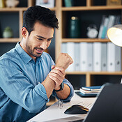 Businessman working in the office with wrist pain, injury or accident ...