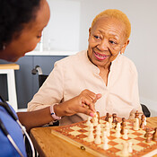 Nurse playing chess with a senior patient after a healthcare ...