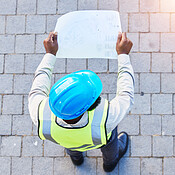 Construction worker, man and building inspection blueprint with ...