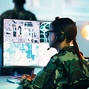 Military control room, computer screen and woman in surveillance, headset and tech for ...