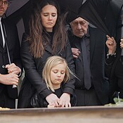 Loss, grief and people at funeral with umbrella, flowers and coffin ...