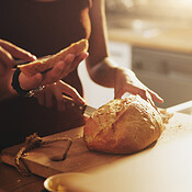 Kitchen, home and hands of people with bread on counter with slice for ...