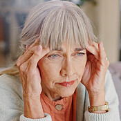 Senior woman, thinking and depressed in lounge, hand and memory of past, retirement and sad in ...