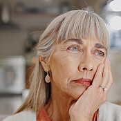 Senior woman, thinking and mental health in lounge, hand and memory of past, retirement and ...