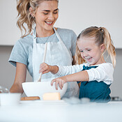 Proud young mother baking with her daughter. Happy little girl mixing a ...