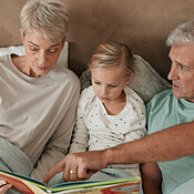 Grandparents, girl and reading fiction in bed for storytelling ...
