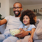 Dad, boy and happy with television or popcorn on sofa in living room ...