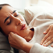 Woman, sore chest and sick in home, virus influenza and laying on bed ...