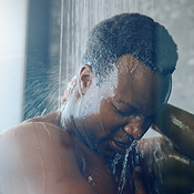 Black man, shower and splash in home, bathroom and washing body for hygiene with self care in ...