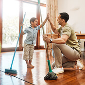 Little caucasian boy helping his father sweep and mop wooden floors for ...