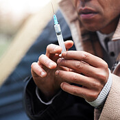 Hands, poverty and homeless with syringe, drugs and tent with addiction ...