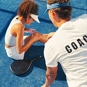 Woman, sport and knee injury with coach for pain, medical assistance or help on outdoor court ...