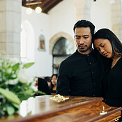 Couple, coffin and hug at funeral in church for death, pay respect or ...