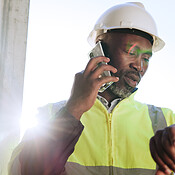 Construction, phone call and man check watch on site for inspection ...