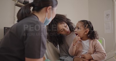 Dentist checking teeth of a young girl inside a consultation room at a ...