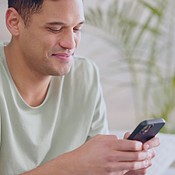 Happy, smile and relax man with phone in house living room or home ...