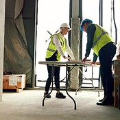 Architecture, man and woman handshake, plan and construction site ...