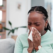 Sneeze, blowing nose and sick black woman with tissue on a sofa for ...