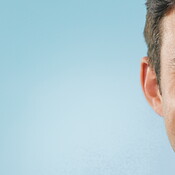 Half face, smile and mockup with a man on a blue background in studio ...