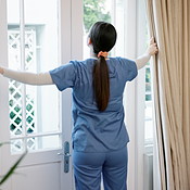Nurse, morning and opening curtains by a door in an assisted living ...