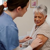 Old woman, nurse help with plaster and elderly care, support and wound from injection with ...