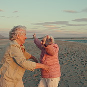 Senior women, friends and hug by sea with hands in air, applause and ...