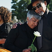 Graveyard, mature man and woman hug at funeral, memorial service or ...