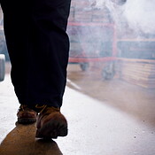 Worker, tool and person with hammer walking in workshop with smoke or ...