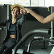 Fitness, women and fist bump for exercise bike challenge at gym with ...