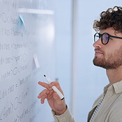 Man, coding and reading on whiteboard in office for review, system ...