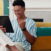 Scroll, success and tablet with man on sofa for online reading, good ...