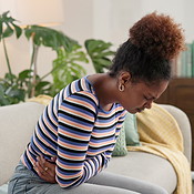 Sick, home and woman with period cramps, pain or stomach ache with ...