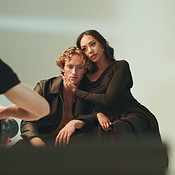 Photographer, set and models on chair in studio with production team ...
