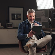 Tablet, filming and man on set reading script for documentary interview ...